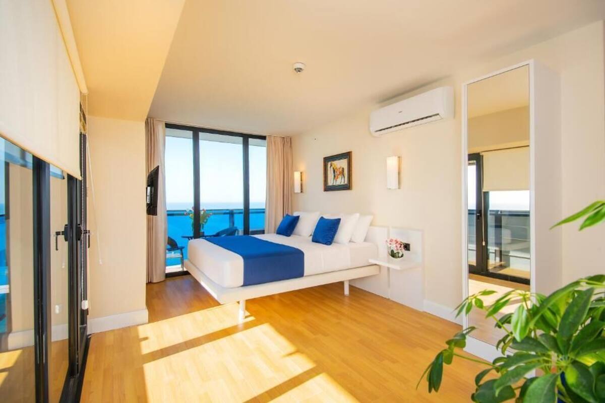 Um quarto moderno com uma cama, mesa de cabeceira, janela com vista e ar condicionado.