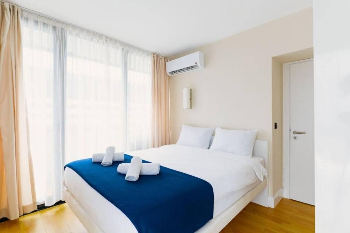 Quarto de hotel com cama, cortinas, ar condicionado e uma porta.