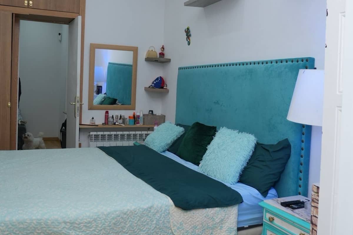 Quarto com cama, mesa de cabeceira, espelho e aparelho de ar condicionado.