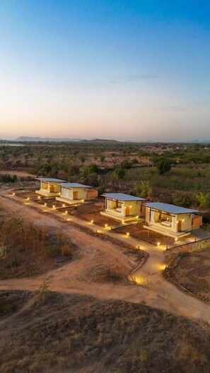 Conjunto de edifícios de dois andares, com várias divisões, interligados por caminhos, situado em uma paisagem árida e aberta.