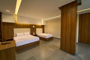 Quarto de hotel moderno com duas camas, cabeceiras de madeira, uma mesa de cabeceira e um pilar de madeira grande.