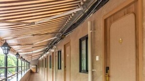 Um corredor com toldo listrado, portas de madeira e chão ladrilhado.