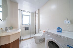 Uma casa de banho moderna com lavatório, sanita, chuveiro e máquina de lavar roupa.