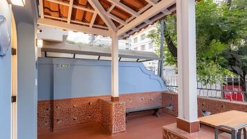 Um pátio externo com área de estar coberta, parede de tijolos e mesa de madeira.
