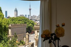 Vista de um horizonte urbano com uma torre imponente, áreas verdes e um edifício com telhado tradicional.