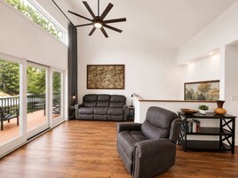 Uma sala de estar moderna com uma janela grande, um ventilador de teto e uma lareira.