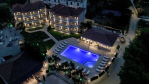 Um hotel com vários andares, piscina, área de estar externa e um pátio bem iluminado.