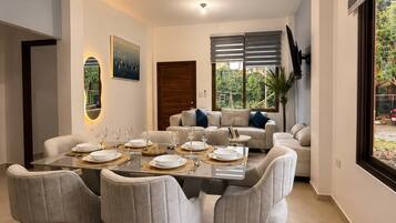 Uma zona de refeições moderna com uma mesa de mármore, cadeiras brancas e um sofá.