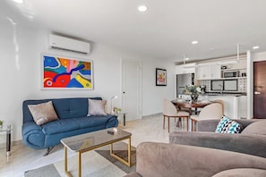 Uma sala de estar moderna com um sofá, uma mesa de centro e um espaço de jantar com cadeiras e uma mesa.