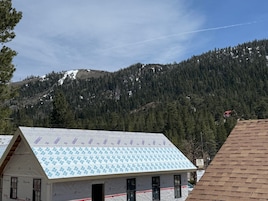 Um edifício com fachada branca e telhado padronizado, com montanhas florestadas ao fundo.
