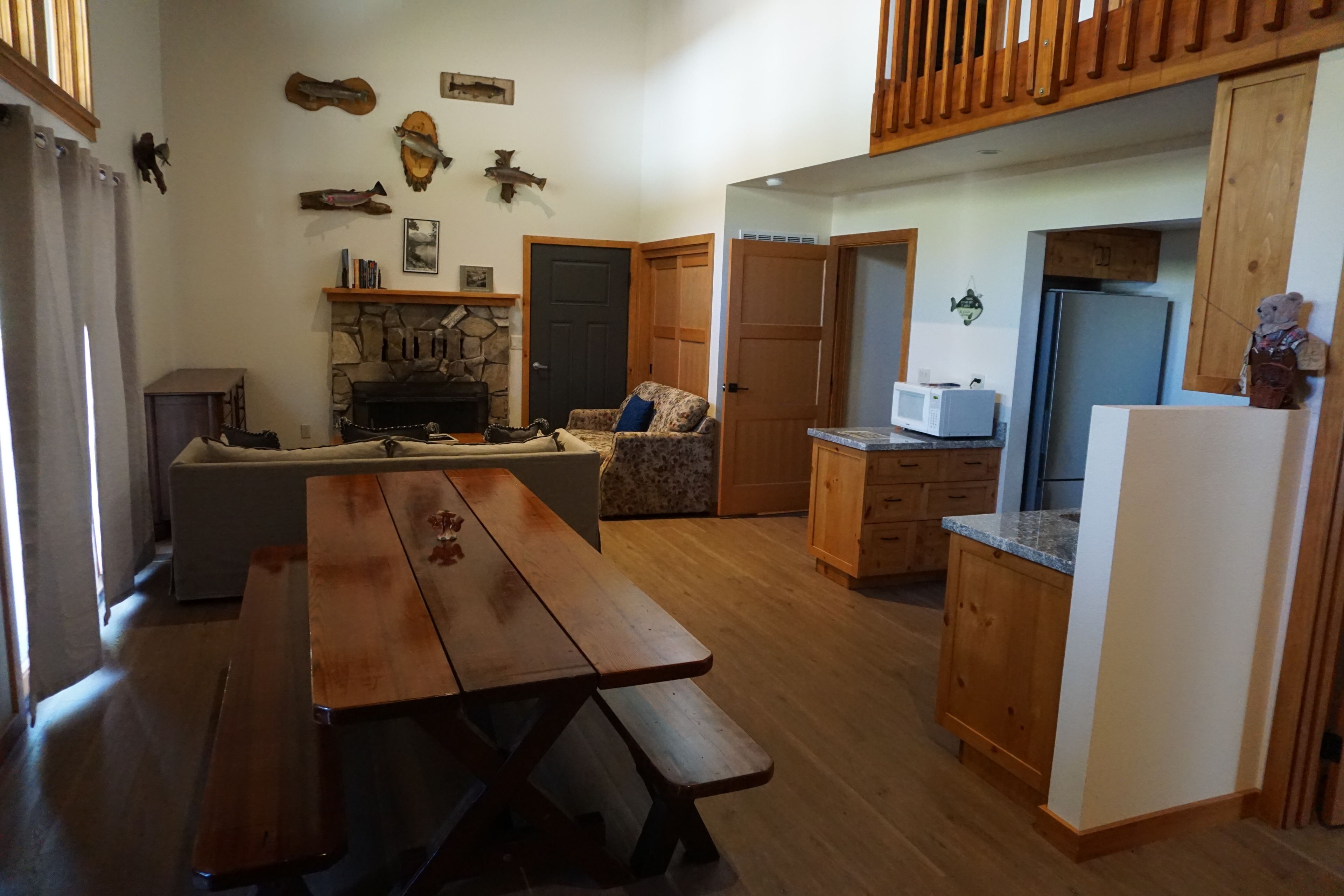 Uma sala de estar acolhedora com um banco de madeira, uma lareira de pedra e uma mesa de jantar.