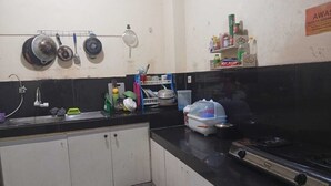 Uma cozinha com bancada preta, fogão, pia e uma prateleira com diversos objetos.