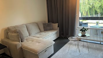 Uma sala de estar com um sofá, uma mesinha e vista para o exterior.