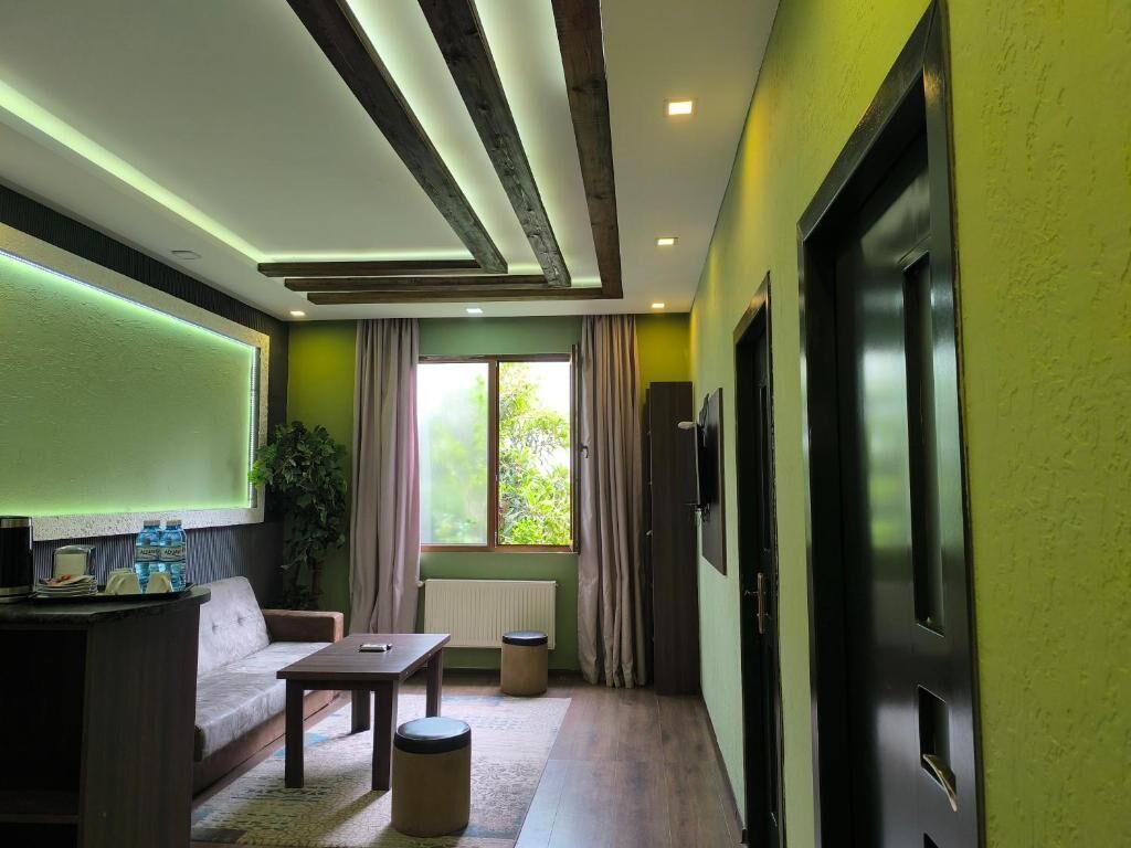 Quarto moderno com sofá, mesa e vista para o verde lá fora.