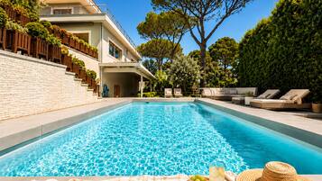 Piscina com espreguiçadeiras e um livro sobre uma toalha.