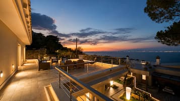 Terraço no telhado com área de estar ao ar livre, vista para o mar e design arquitetônico bem iluminado.