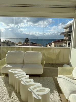 Varanda com um sofá branco, uma poltrona branca e um tapete branco com design exclusivo.