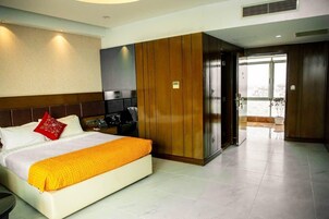 Quarto de hotel com cama, guarda-roupa de madeira, secretária com cadeira e vista para o exterior.