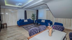 Uma sala de estar moderna com um sofá azul, uma mesa de jantar e um vaso de planta.