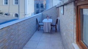 Uma varanda com mesa e cadeiras, uma janela e vista para prédios.