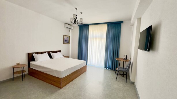 Quarto de hotel com uma cama, televisão, mesa pequena e uma cadeira.