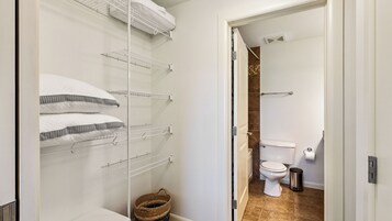 Casa de banho com sanita, um contentor de lixo e zona de duche com porta de vidro.