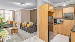 Um apartamento moderno com sala de estar, sofá, mesa de centro e cozinha equipada com frigorífico e micro-ondas.