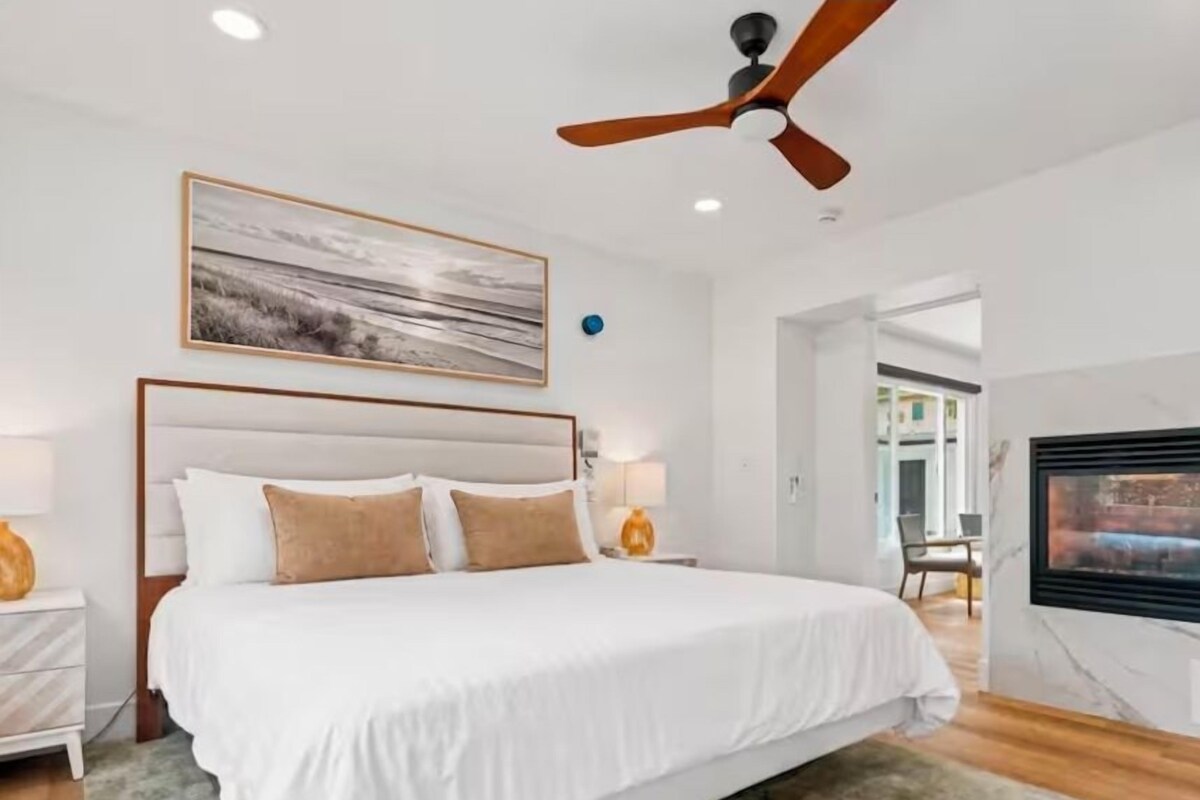 Quarto com cama, ventilador de teto, um quadro e uma televisão.