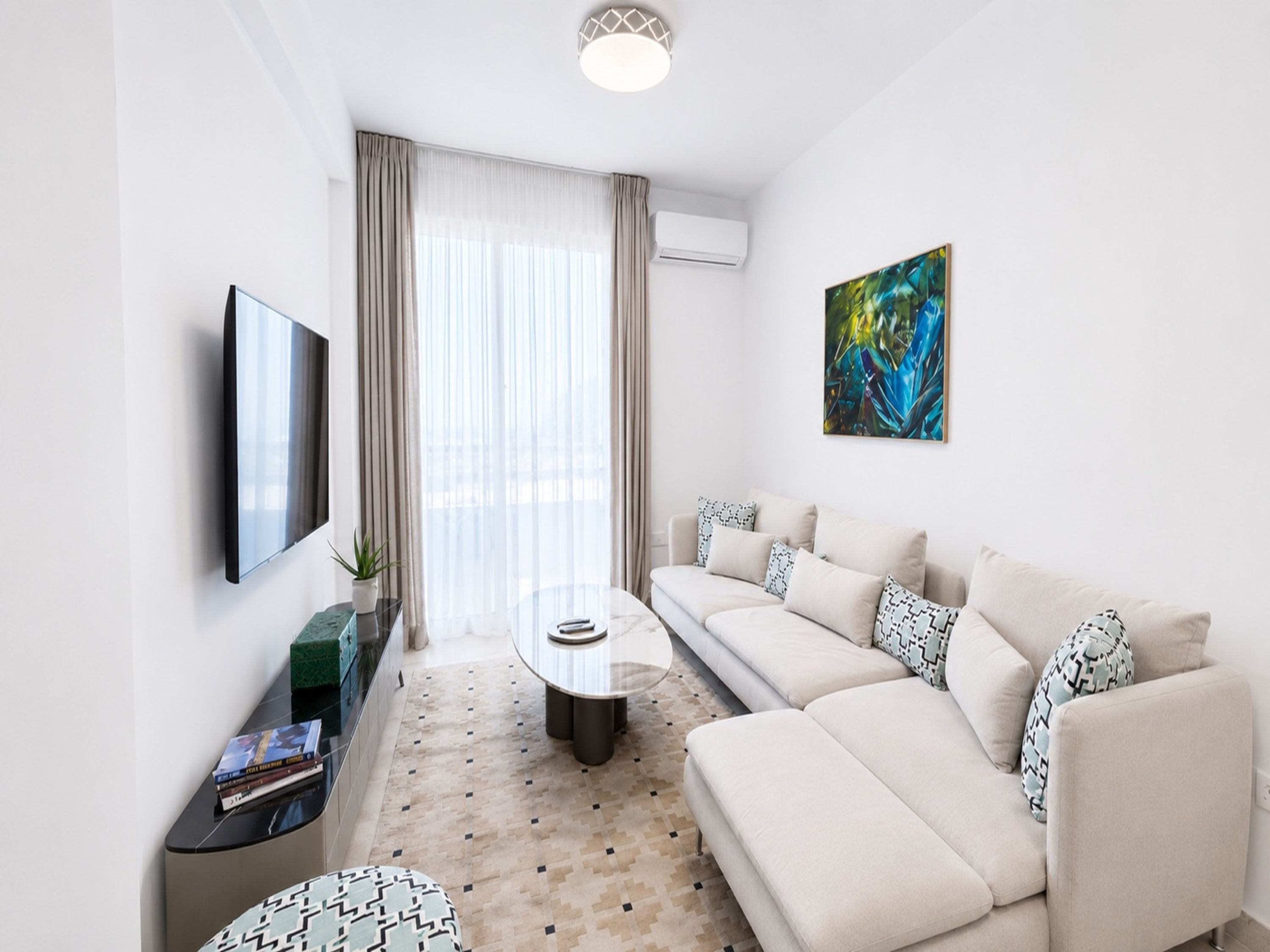 Uma sala de estar moderna com sofá, mesa de centro, televisão de tela plana e um quadro na parede.