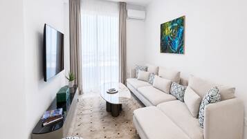 Uma sala de estar moderna com sofá, mesa de centro, televisão de tela plana e um quadro na parede.