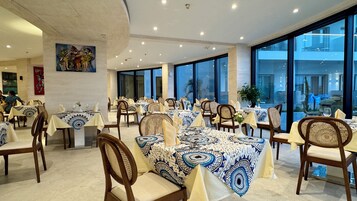 Um restaurante com várias mesas, cadeiras e uma grande janela que oferece vista para o exterior.