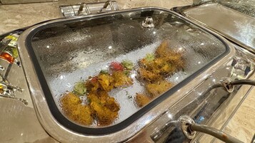 Uma pia de aço inoxidável com tampa de vidro, gotas de água e uma torneira.