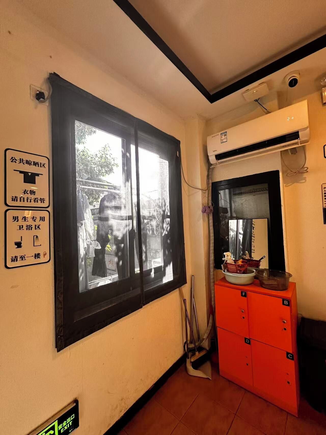 Quarto com janela, ar condicionado e armário com gavetas identificadas.