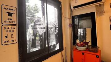 Quarto com janela, ar condicionado e armário com gavetas identificadas.