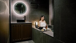 Uma casa de banho moderna com um espelho redondo, uma sanita preta e um porta-toalhas.