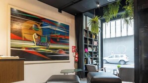 Um interior moderno com uma grande pintura abstrata, uma estante de livros e vista para a rua.