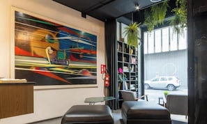 Um interior moderno com uma grande pintura abstrata, uma estante de livros e vista para a rua.