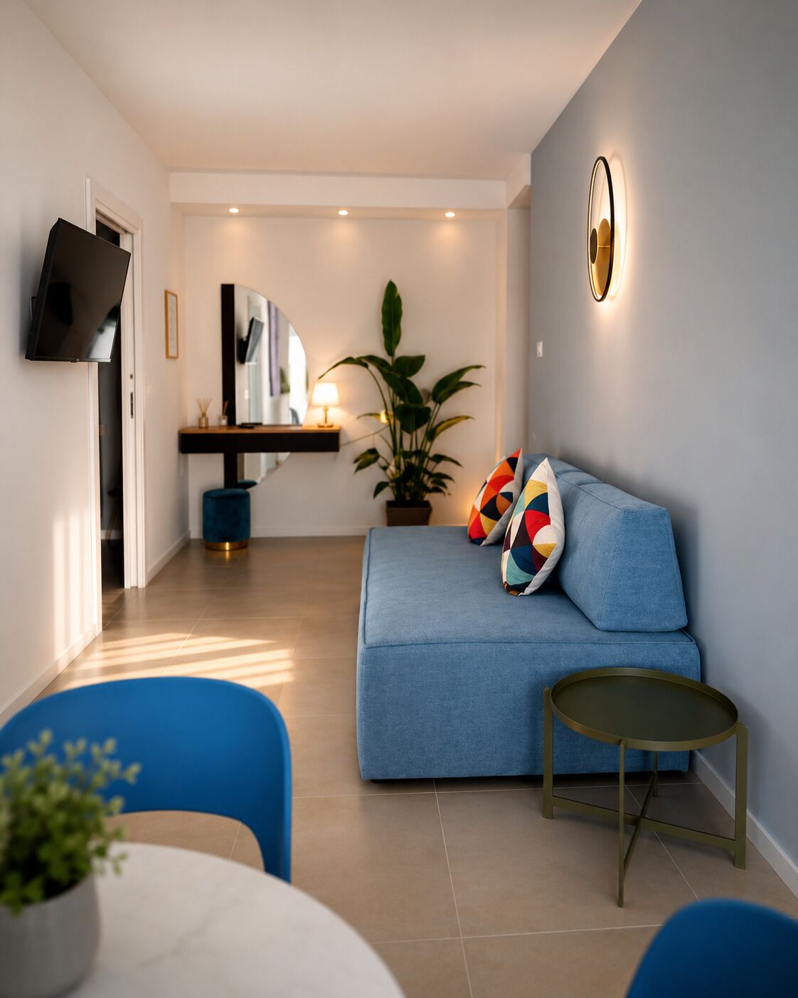 Uma sala de estar moderna com um sofá, uma mesinha redonda e uma televisão na parede.