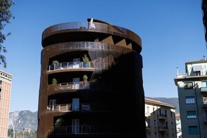 Um edifício com vários andares, varandas, um design em espiral e céu azul ao fundo.