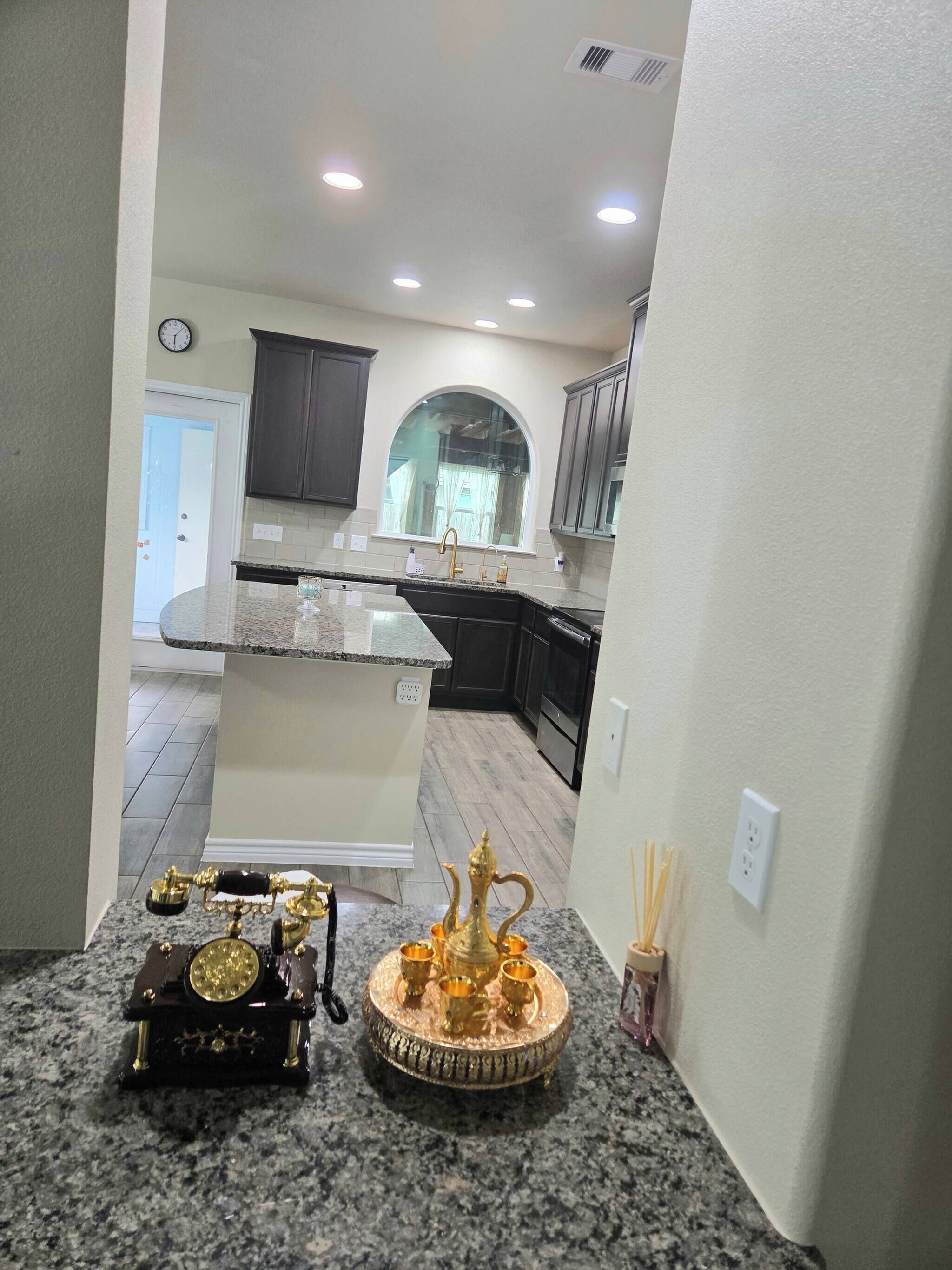 Cozinha com bancadas de granito, um objeto decorativo dourado e vista para a área de estar adjacente.