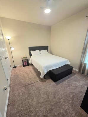 Quarto com cama, luminária de cabeceira e ventilador de teto.