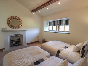 Quarto com duas camas, lareira, janela com persianas e espelho na parede.