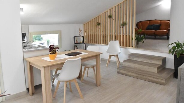 Um interior moderno com uma mesa de jantar de madeira, cadeiras brancas, uma escada e um sofá de couro.