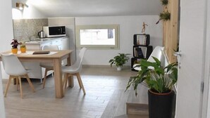 Cozinha moderna com micro-ondas, pia e armários, área de jantar com mesa e cadeiras, e escada que leva a um andar superior.