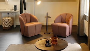 Uma sala de estar moderna com dois poltronas, uma mesa de centro redonda e um abajur.