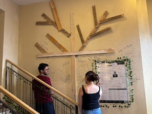 Escadaria com vigas de madeira e parede com diversas inscrições e um quadro de cardápio.