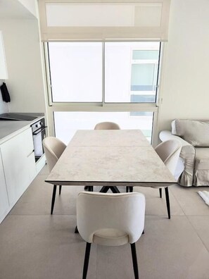 Uma cozinha moderna com mesa e cadeiras, janelas amplas e um sofá.