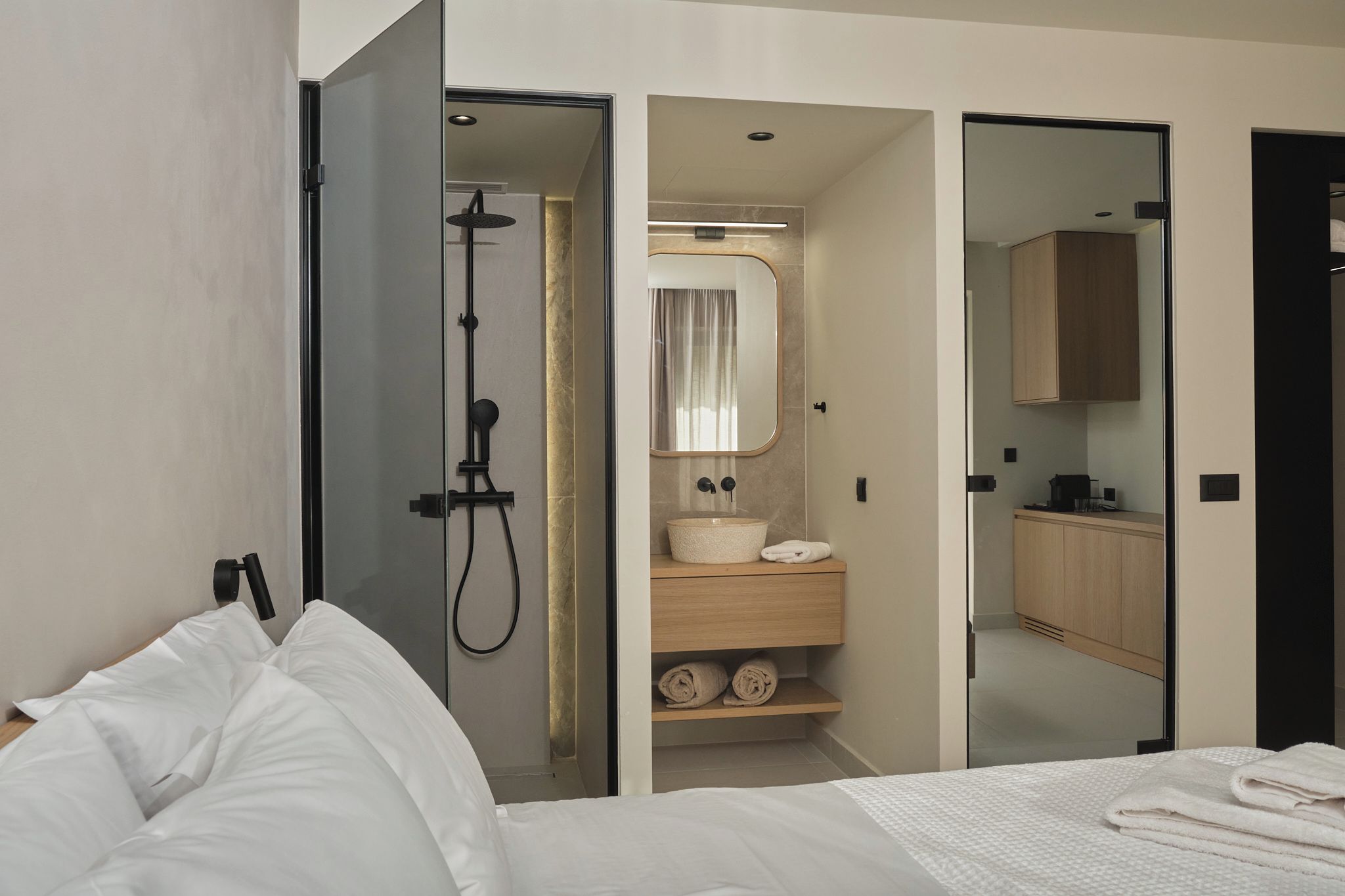 Quarto de hotel com cama, banheiro com pia e espelho, e um closet espaçoso.