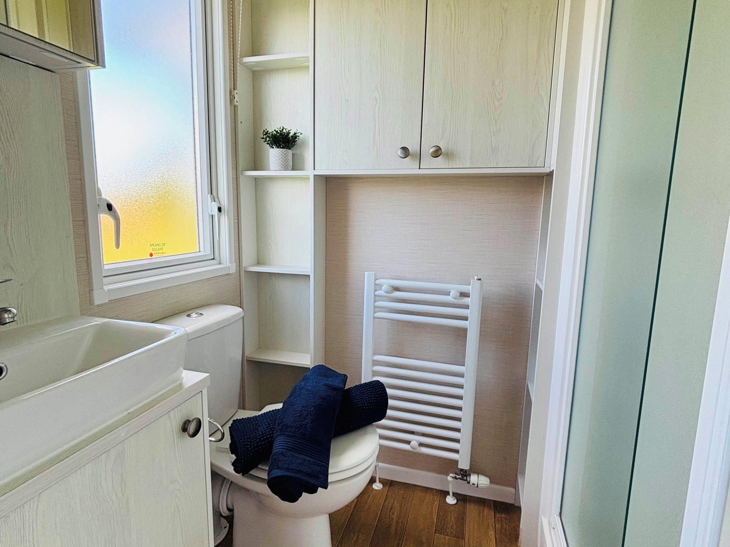 Casa de banho com sanita, radiador branco e janela com vista.