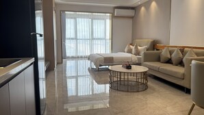 Quarto de hotel moderno com uma cama grande, um sofá, uma mesa de centro e uma televisão.